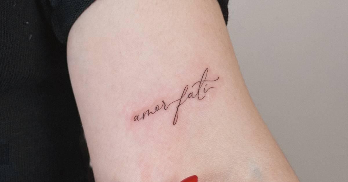 "Amor fati" lettering tattoo located on the bicep.