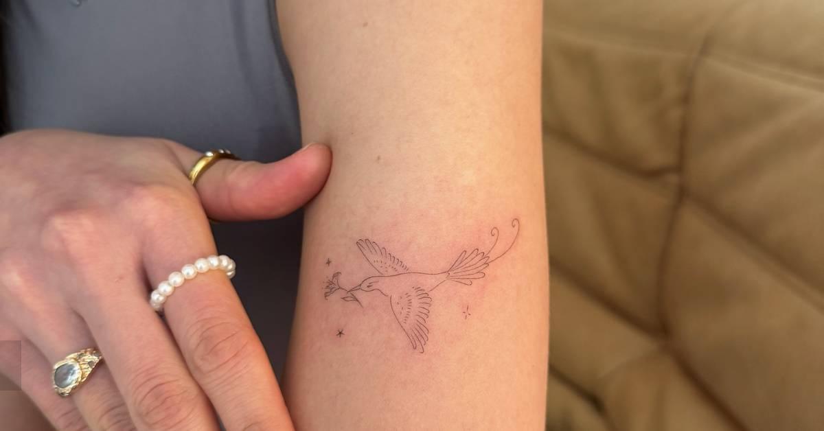Little dove tattoo in fine line style placed on the