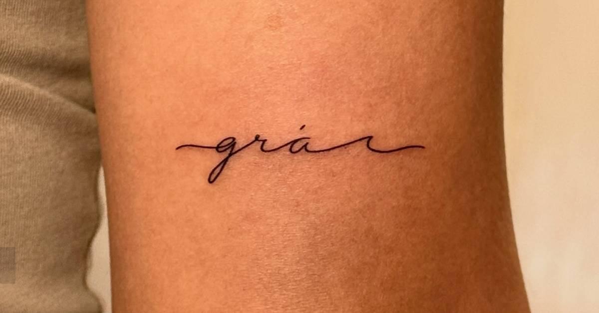 lettering tattoo of the word "grá" and wave placed on