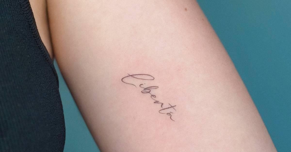 Handwritten lettering tattoo of the word "liberta"