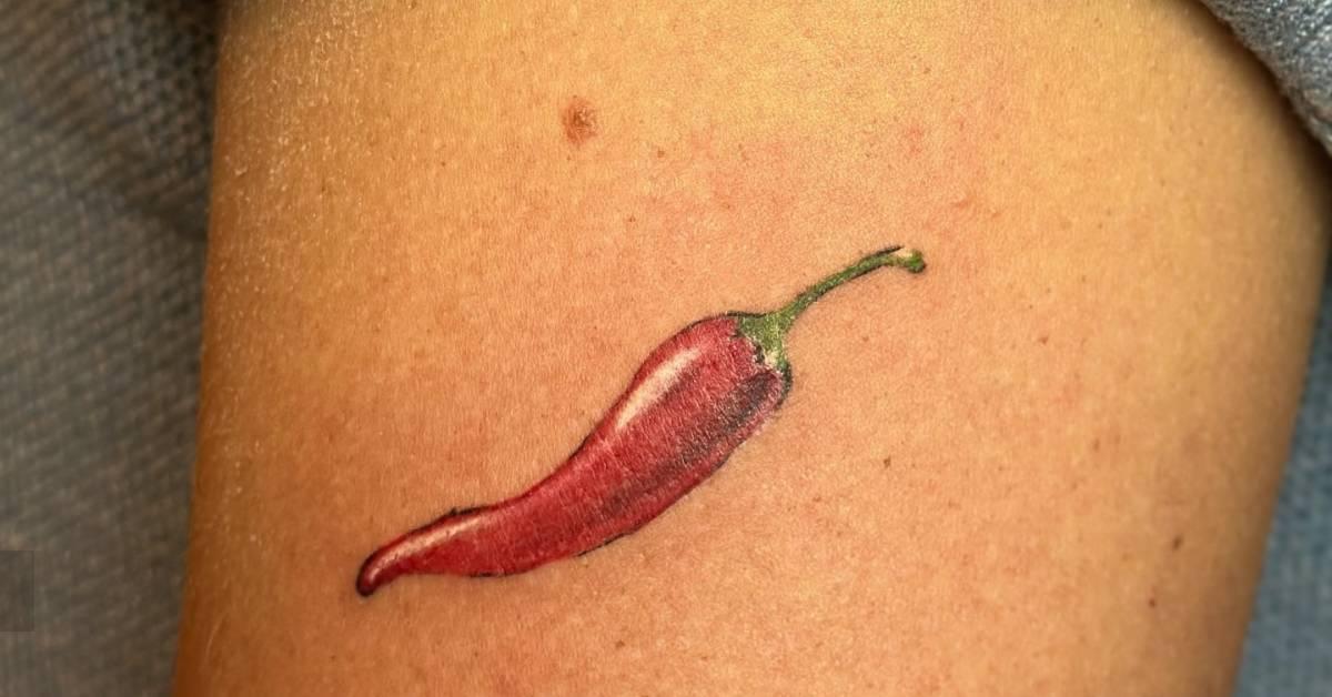 Illustrative style red chili tattoo located on the