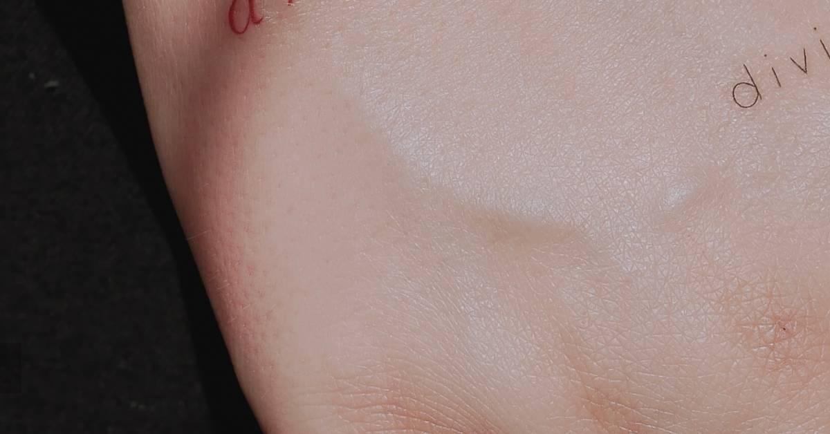 Word "art" in red ink tattooed on the hand.