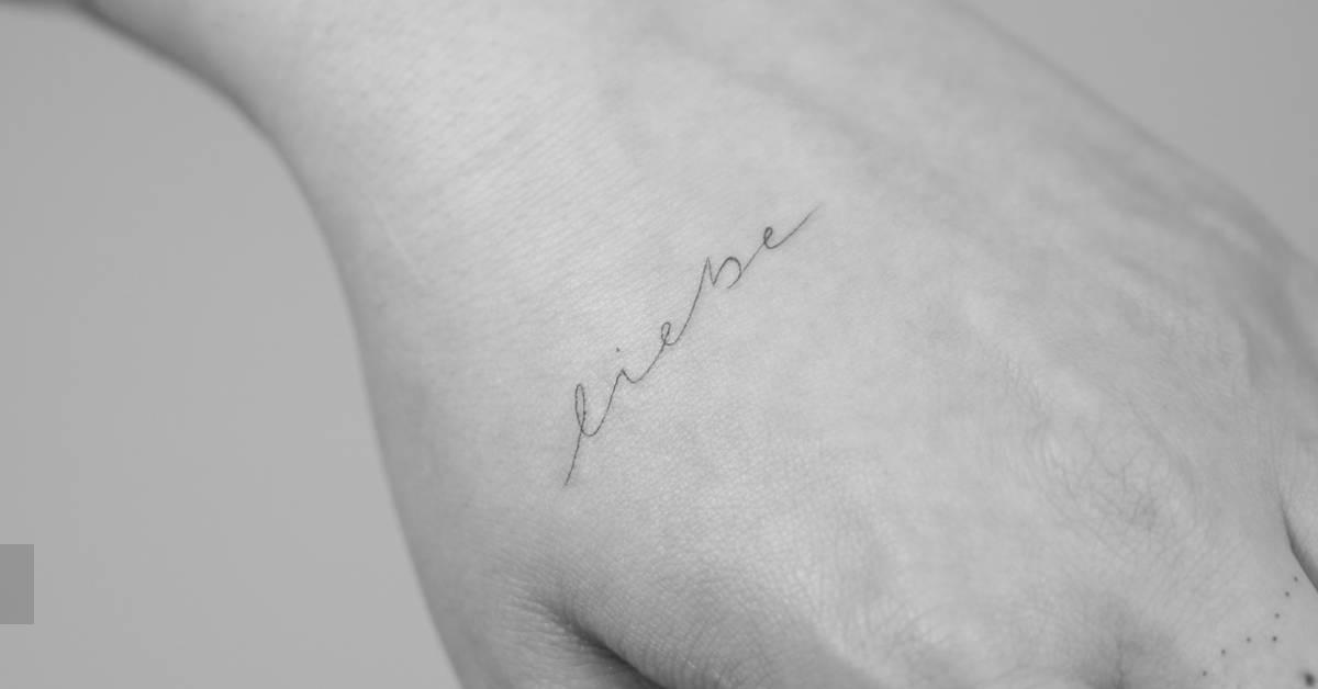 Handwritten font word "liebe" tattooed on the hand.