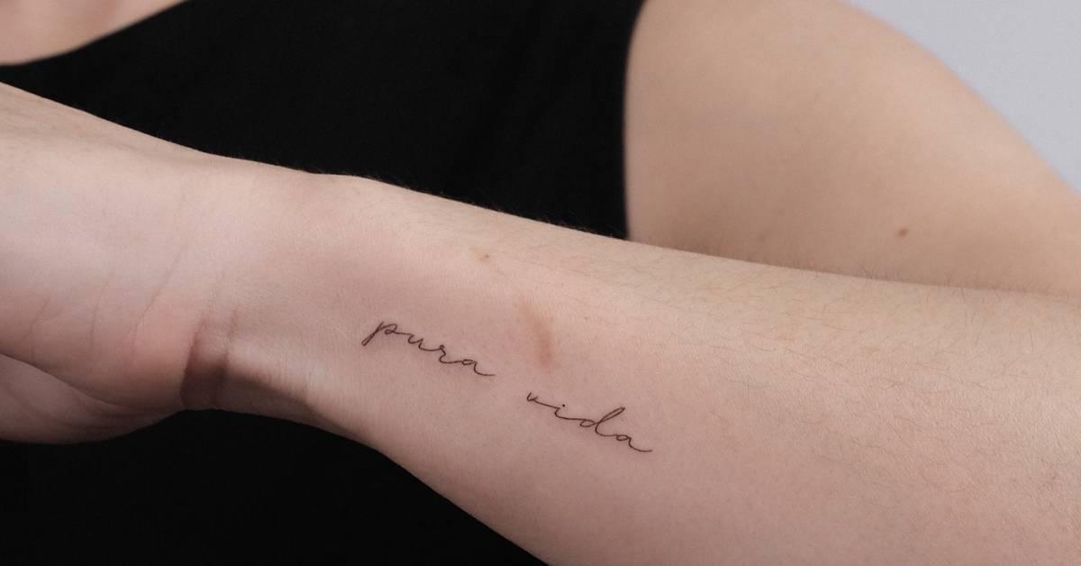 Lettering tattoo that says "pura vida" handwritten on