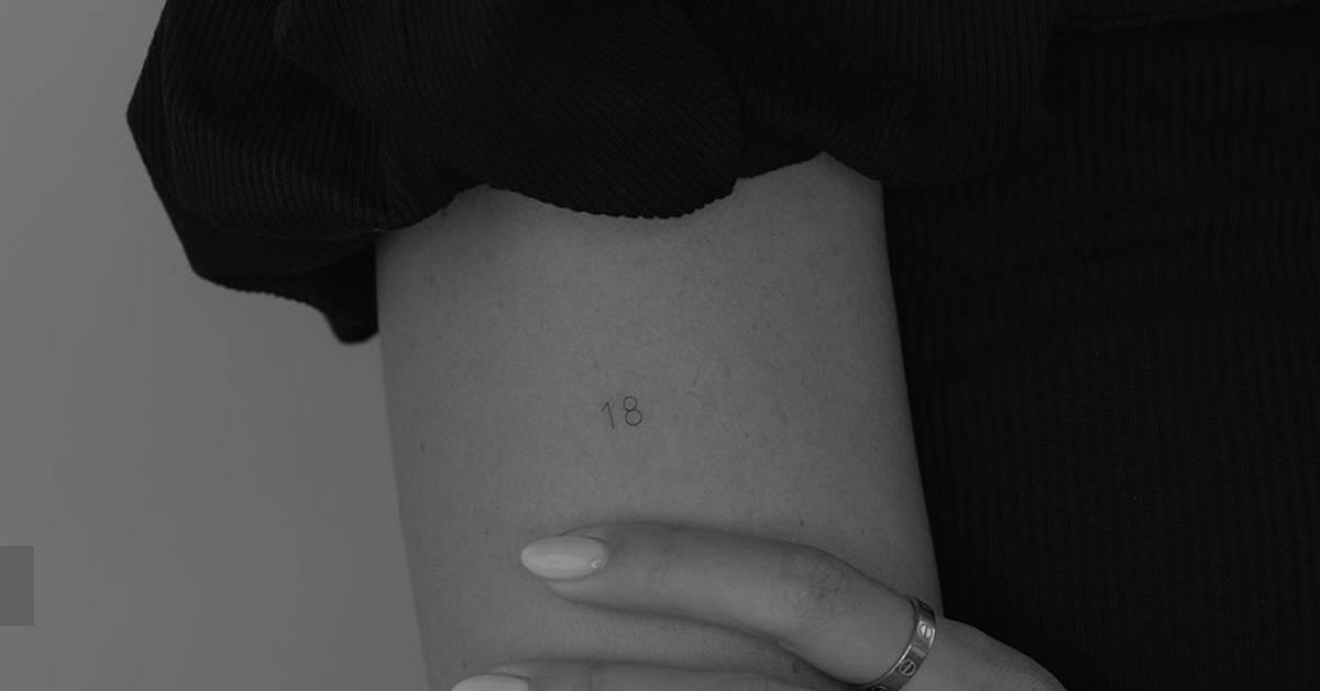 Tiny lettering tattoo of the number "18" located on the