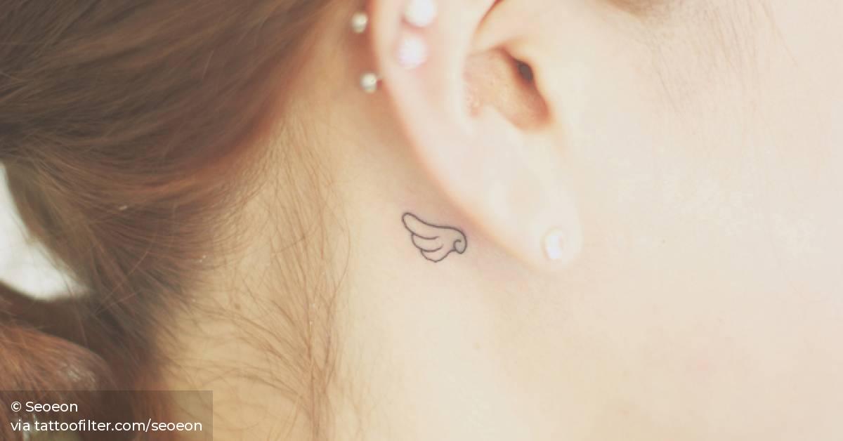 Small minimalist wing tattoo behind the right ear.