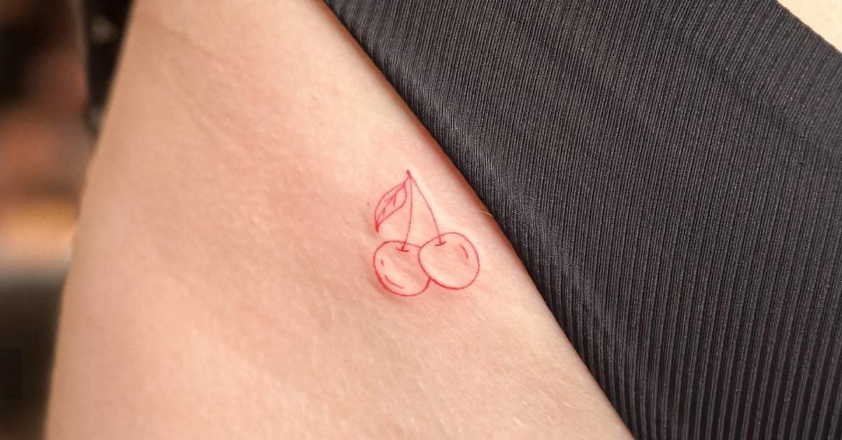 Fine line style red cherries tattoo done on the pelvis.