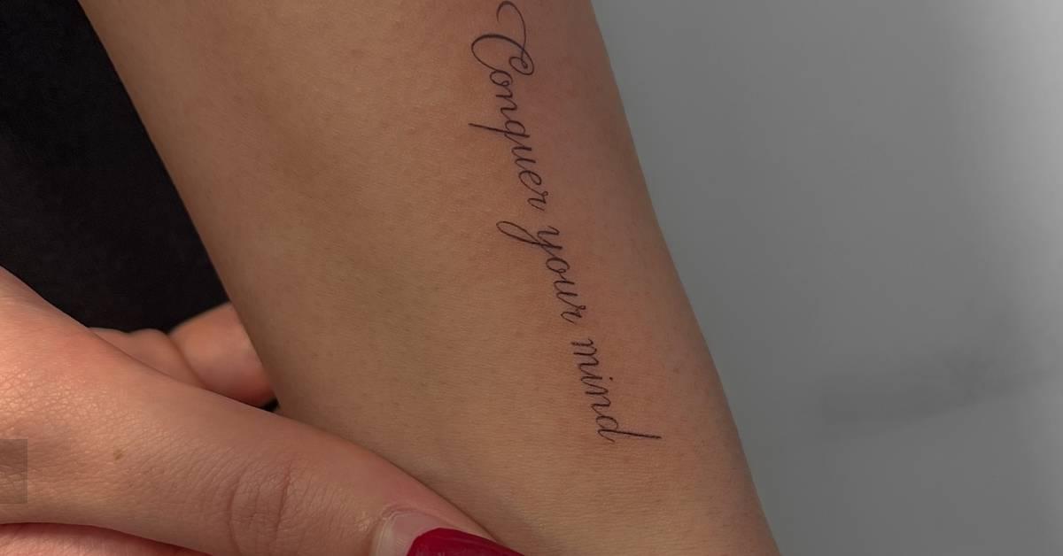 "Conquer your mind" lettering tattoo placed on the