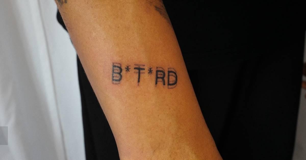 Blurry effect word "bâtard" tattooed on the wrist.