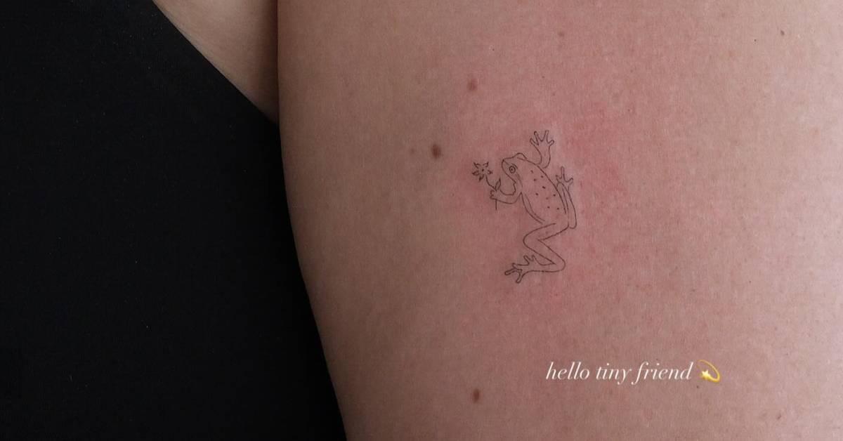 Tiny frog tattoo in fine line style located on the
