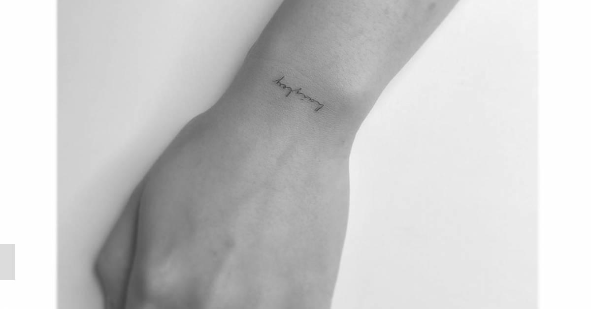 Handwritten font name tattooed on the wrist.