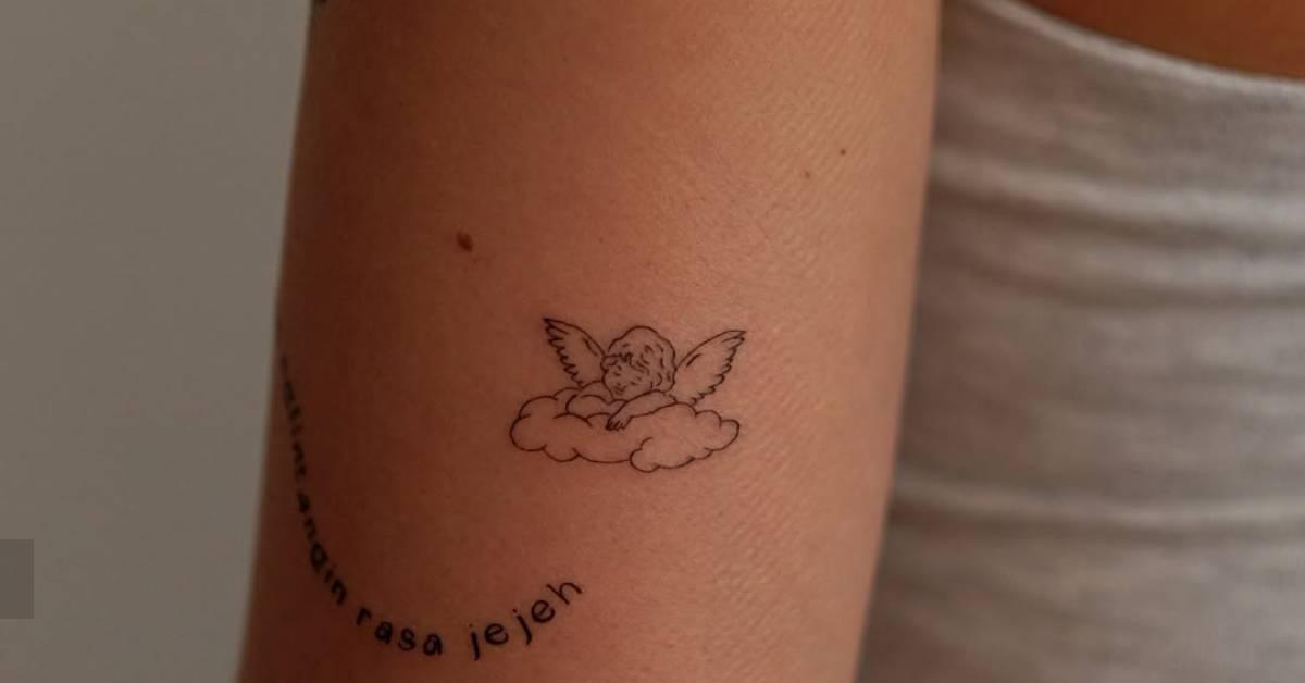 Sleeping cherub in fine line style tattooed on the