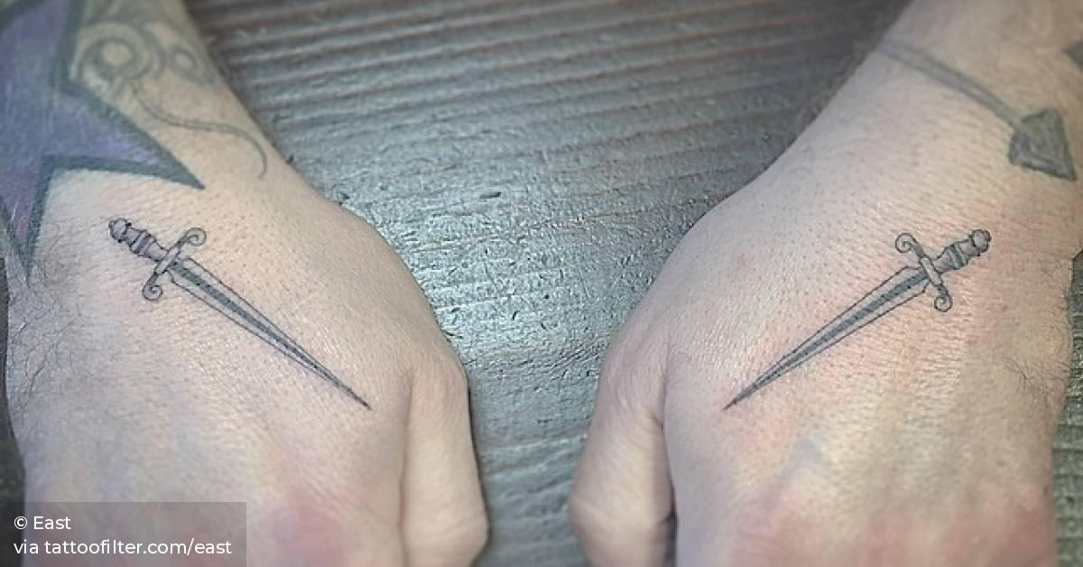 Matching dagger tattoos on both hands.