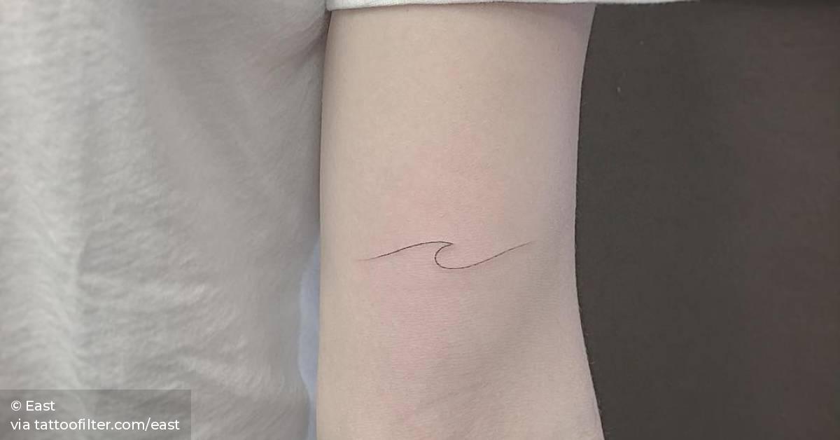 Small fine line style wave tattoo on the left bicep.