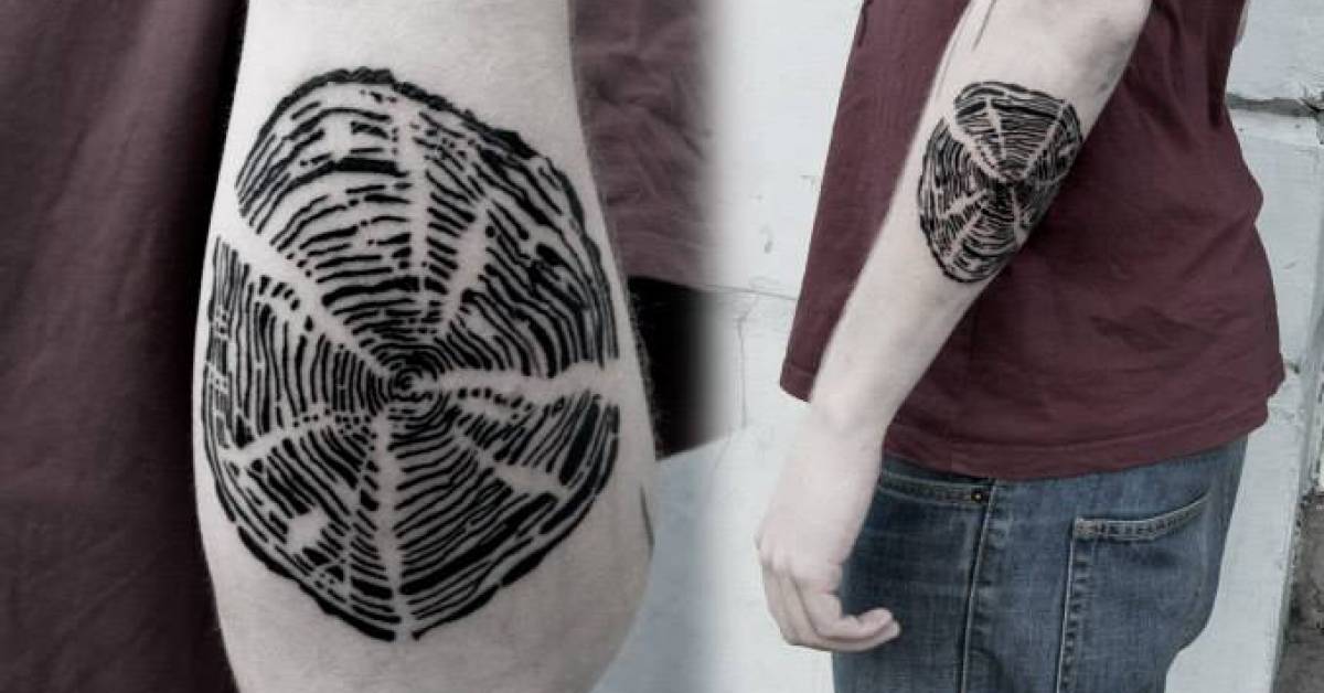 Tree-ring tattoo on the left forearm.