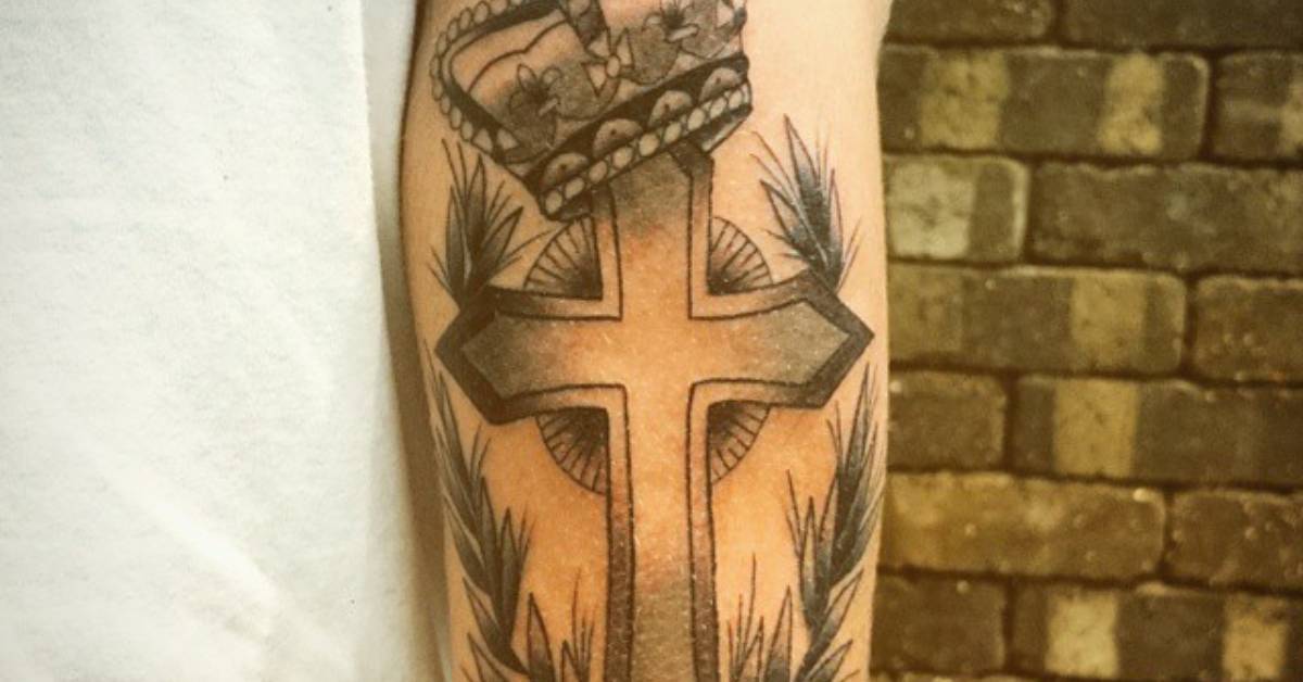 Bicep tattoo of a christian cross, a crown and a laurel