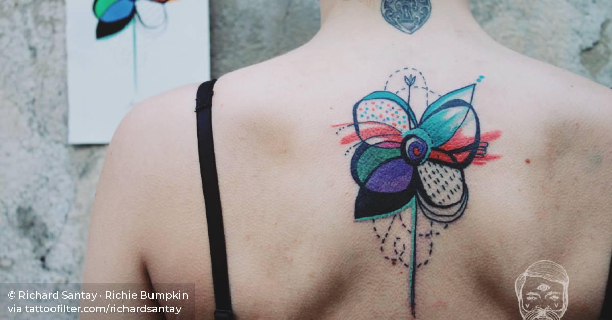 Abstract flower tattoo on the upper back. Design by