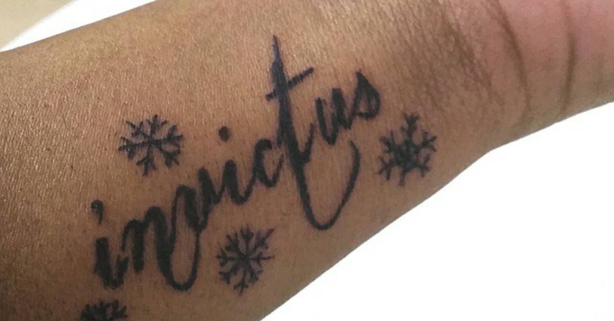 Forearm tattoo saying "Invictus" together with four